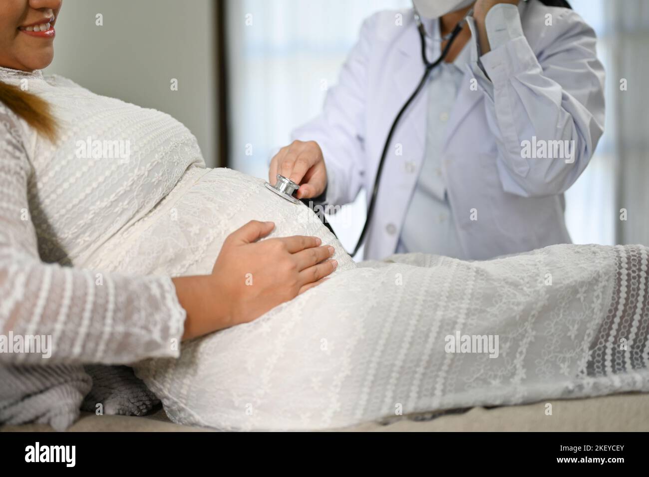 Professional female doctor or obstetrician listening baby's heartbeat ...