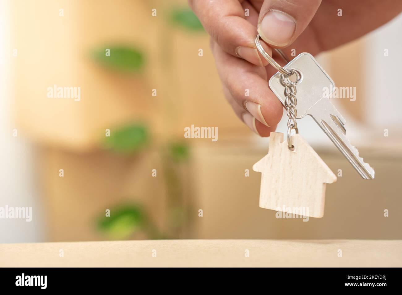 Hand holding new home keys on house shaped keychain real state moving ...