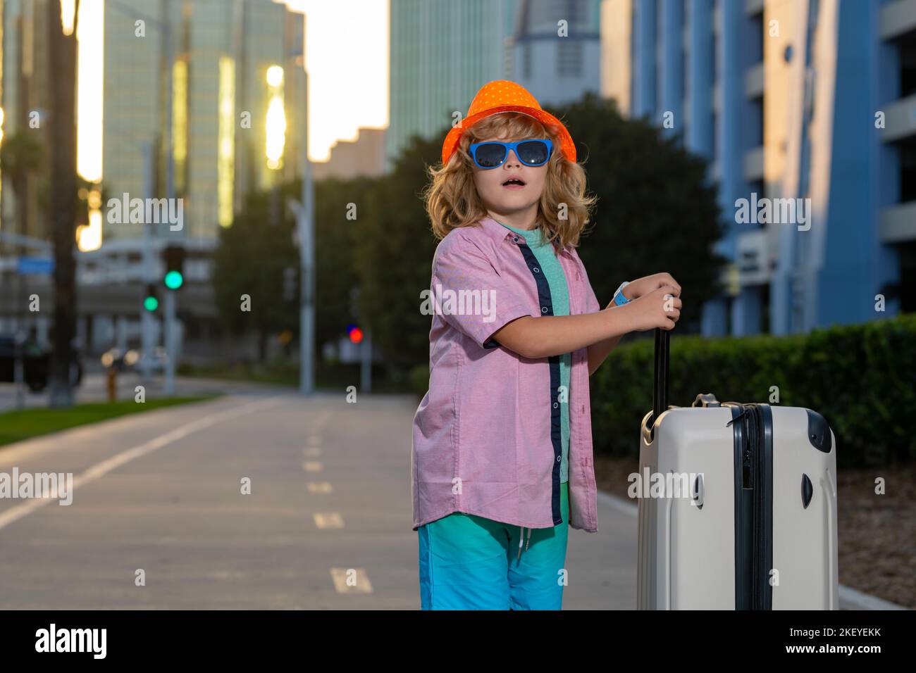 Kids travel. Happy child boy carrying travel suitcases outdoor on city ...