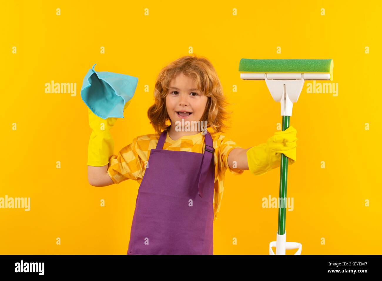 Child doing housework. Studio portrait of child use duster and gloves ...