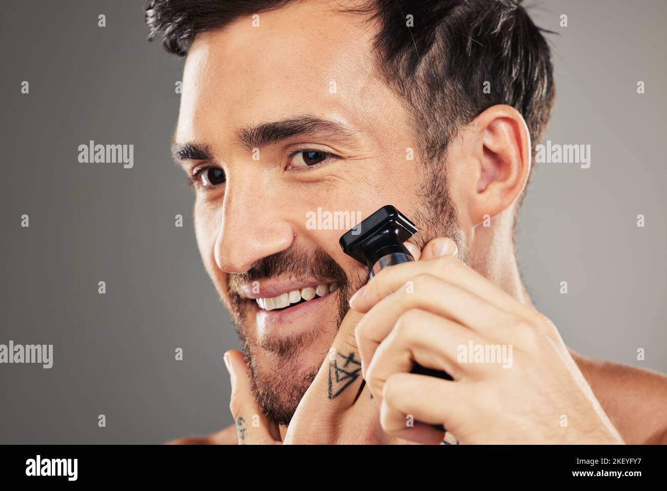 Face, skincare and man shaving with razor in studio isolated on gray ...