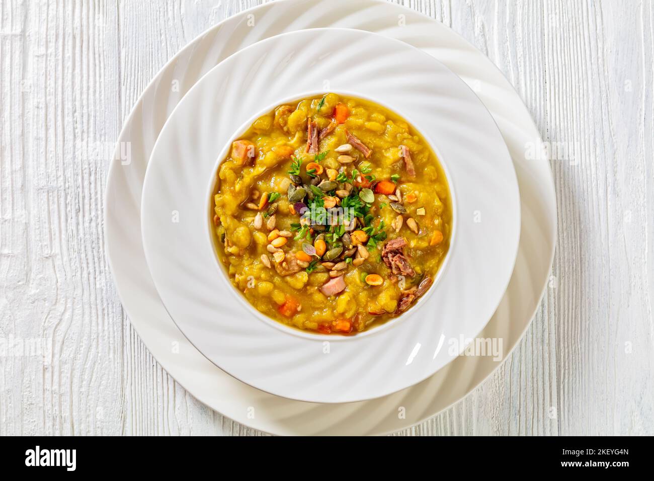 split pea soup Hernekeitto with ham in white bowl on white wood table ...