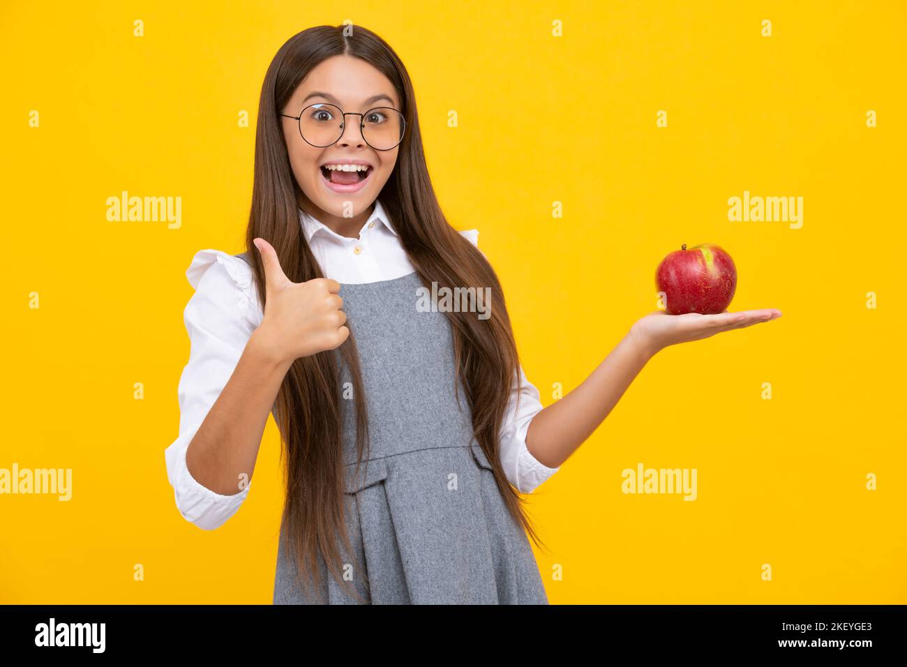 Child girl eating an apple over isolated yellow background. Tennager ...