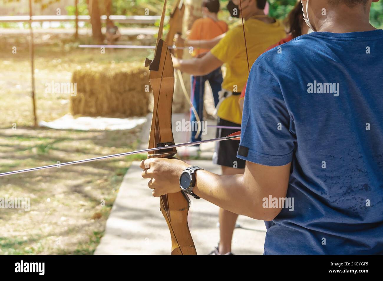 Back view of young man aims archery bow and arrow to colorful target in ...