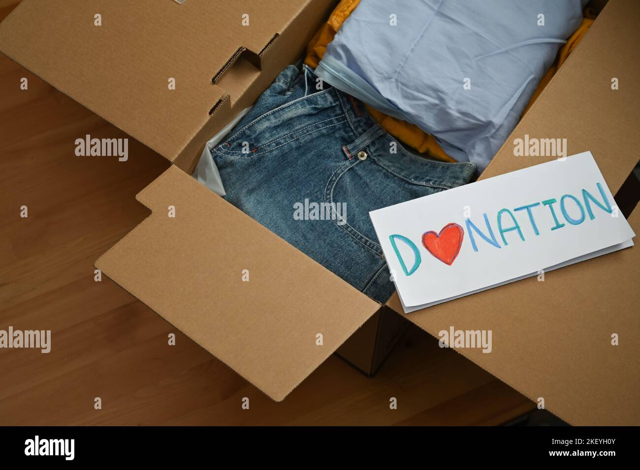 Donation box with clothes on wooden table. Charity, donation and reuse ...