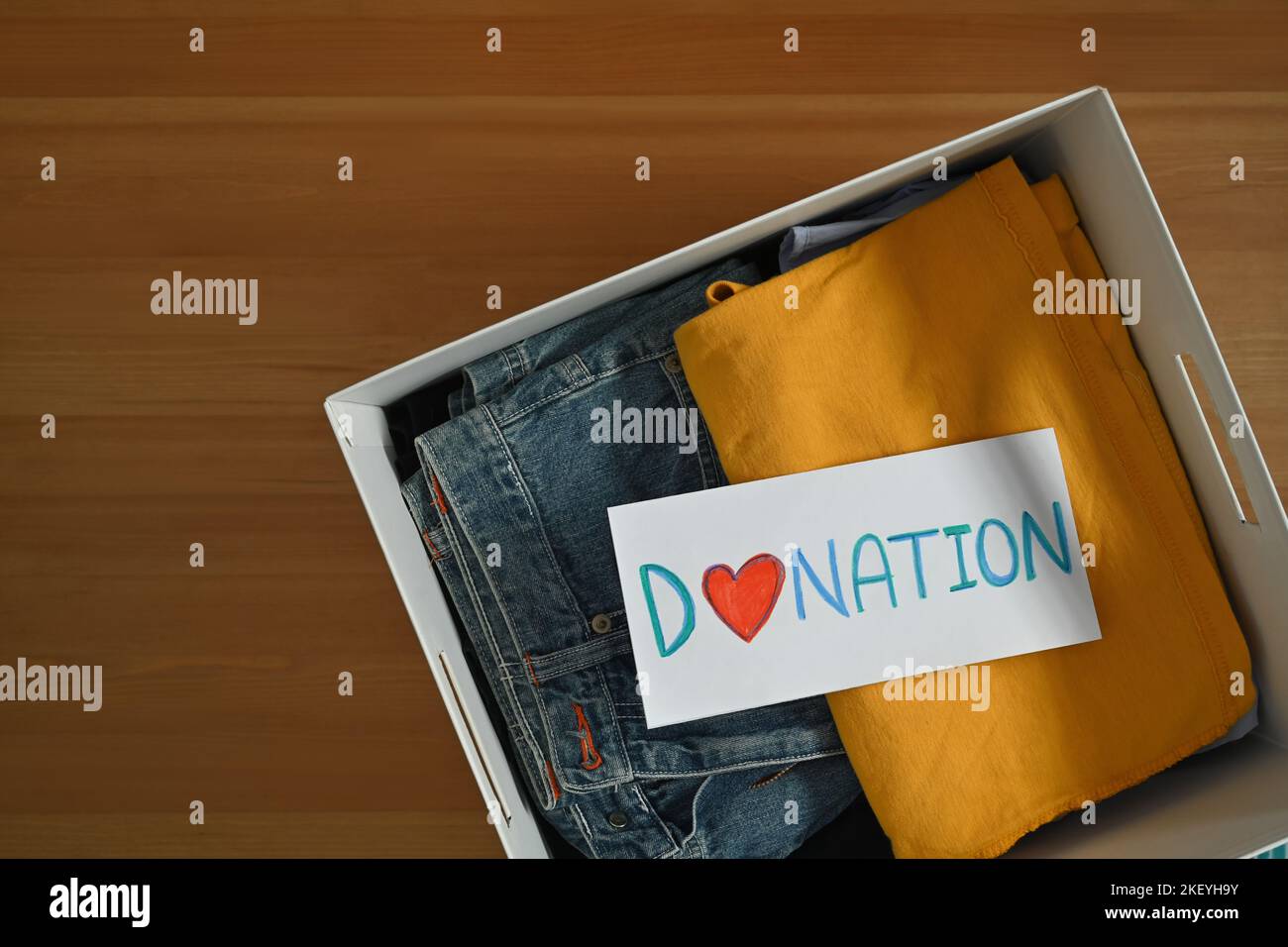 Carton boxes with clothes and donation label on wooden table. Charity ...