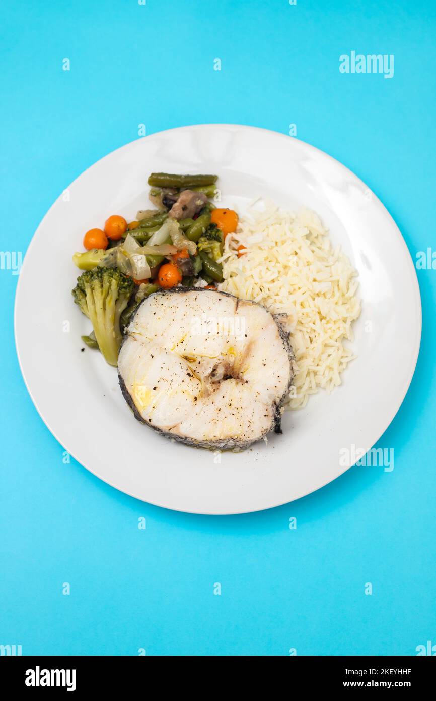 baked vegetables with boiled fish on white plate on blue Stock Photo ...