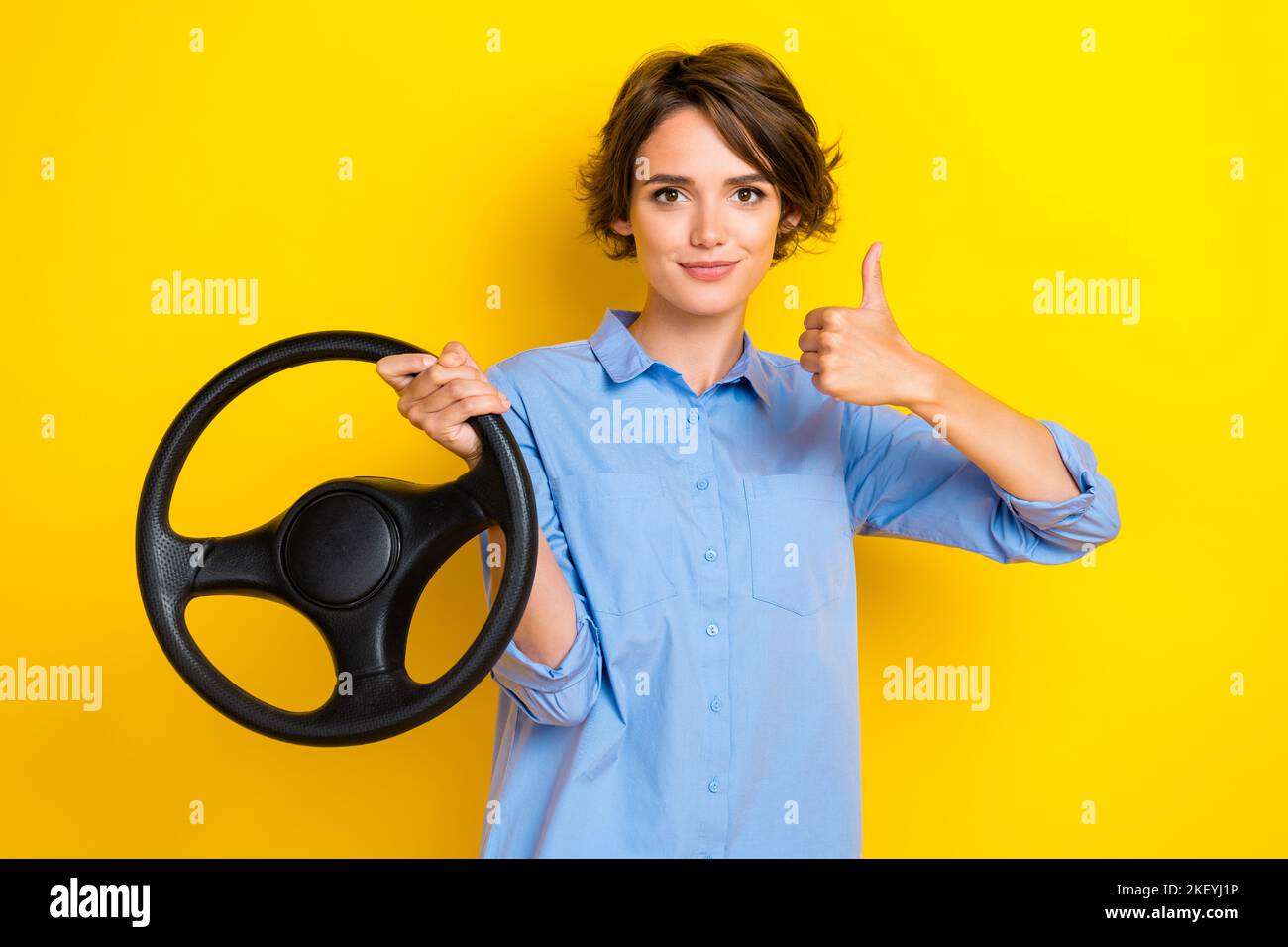 Photo of confident shiny lady wear blue shirt driving car showing thumb ...