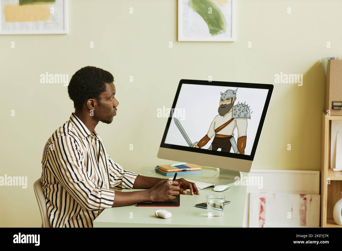 Young creative graphic designer with stylus and tablet sitting by ...