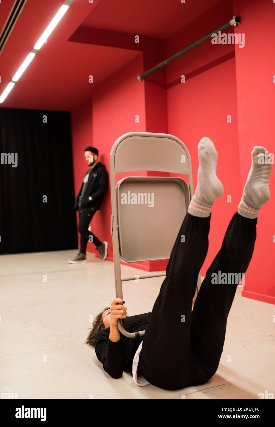 Woman lying on floor holding folded chair for expressive exercise at ...