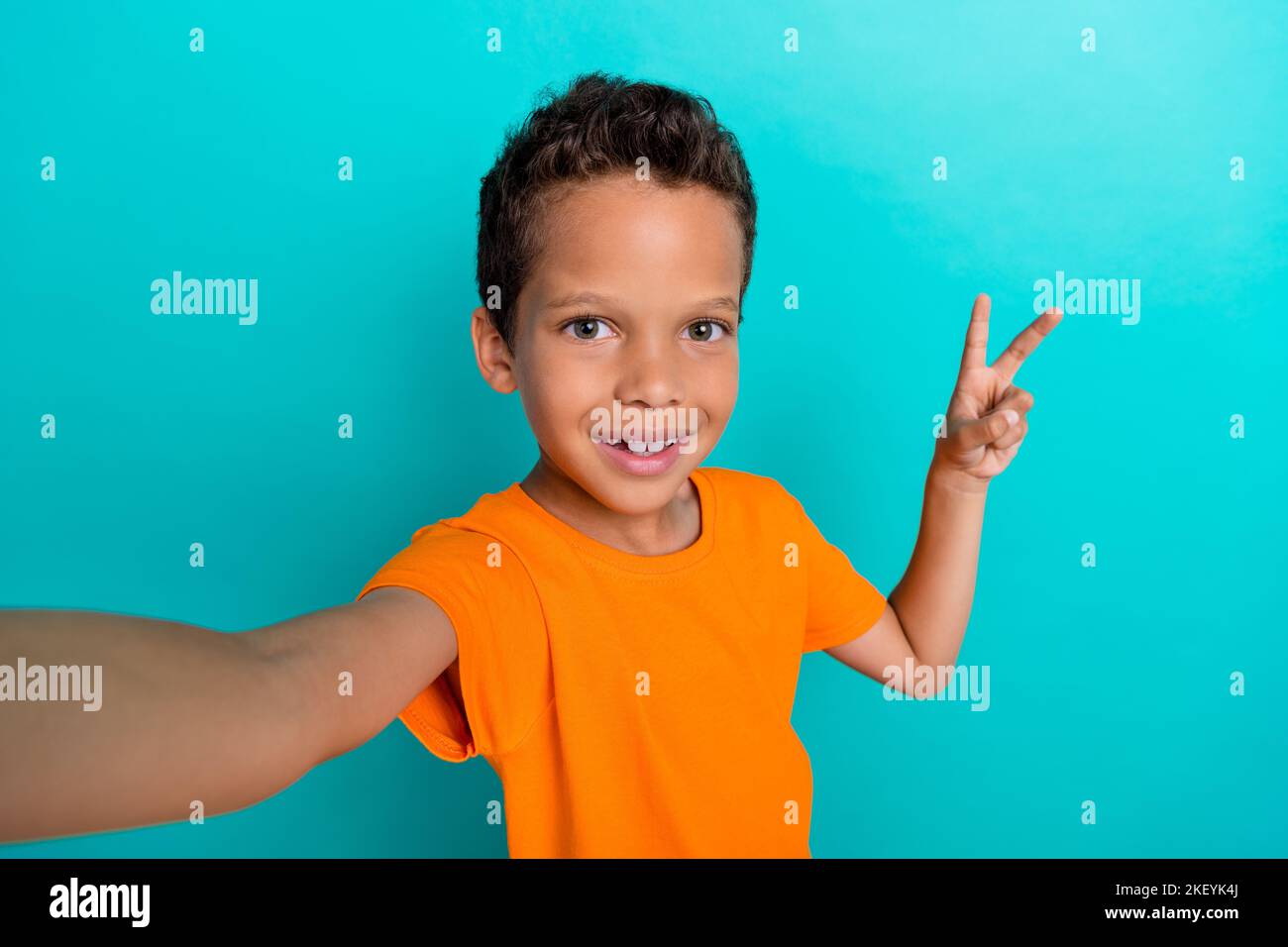 Photo of cute funny little guy dressed orange t-shirt showing v-sign ...