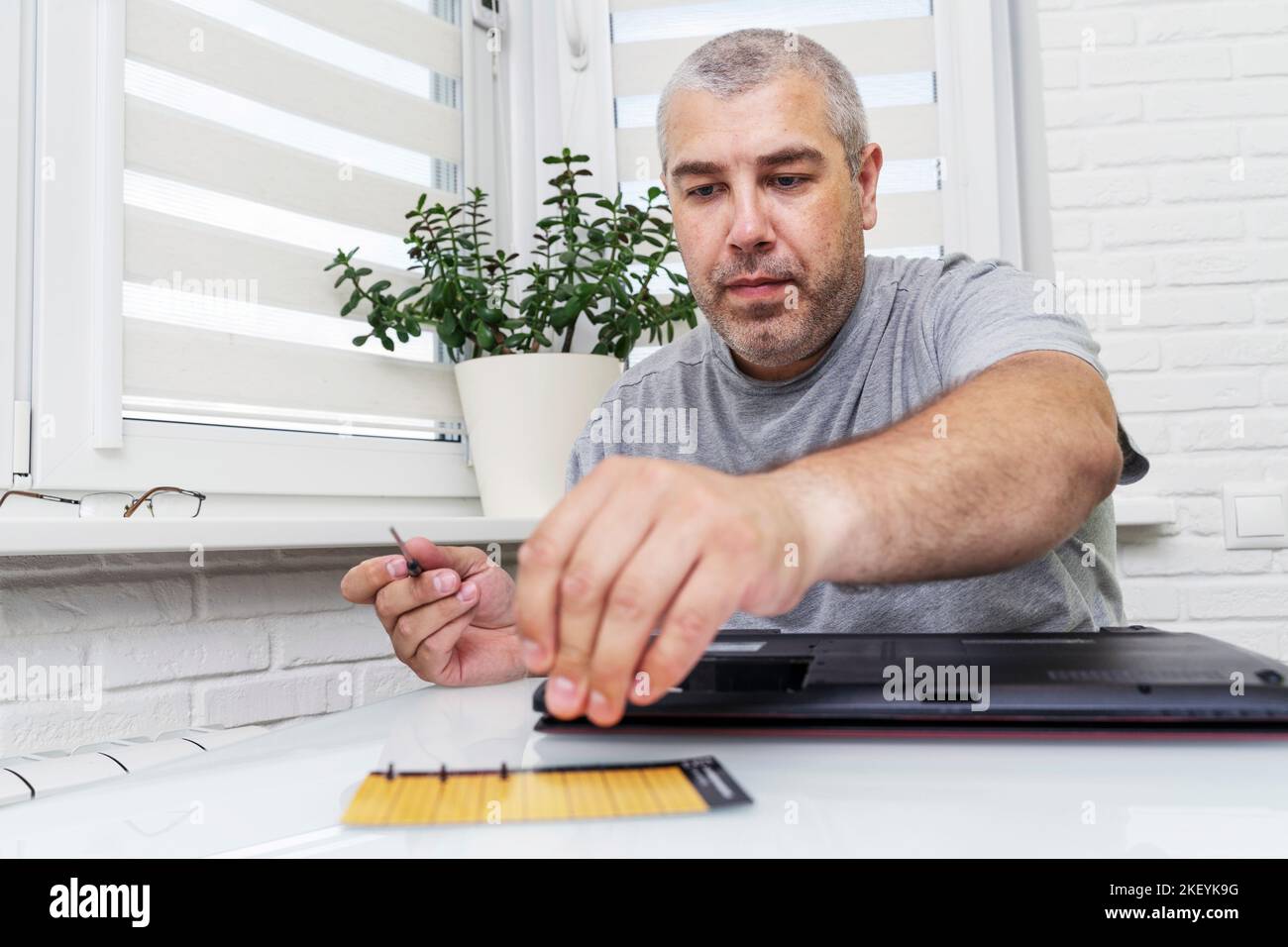 Closeup shot of a man taking apart a laptop with a screwdriver and ...