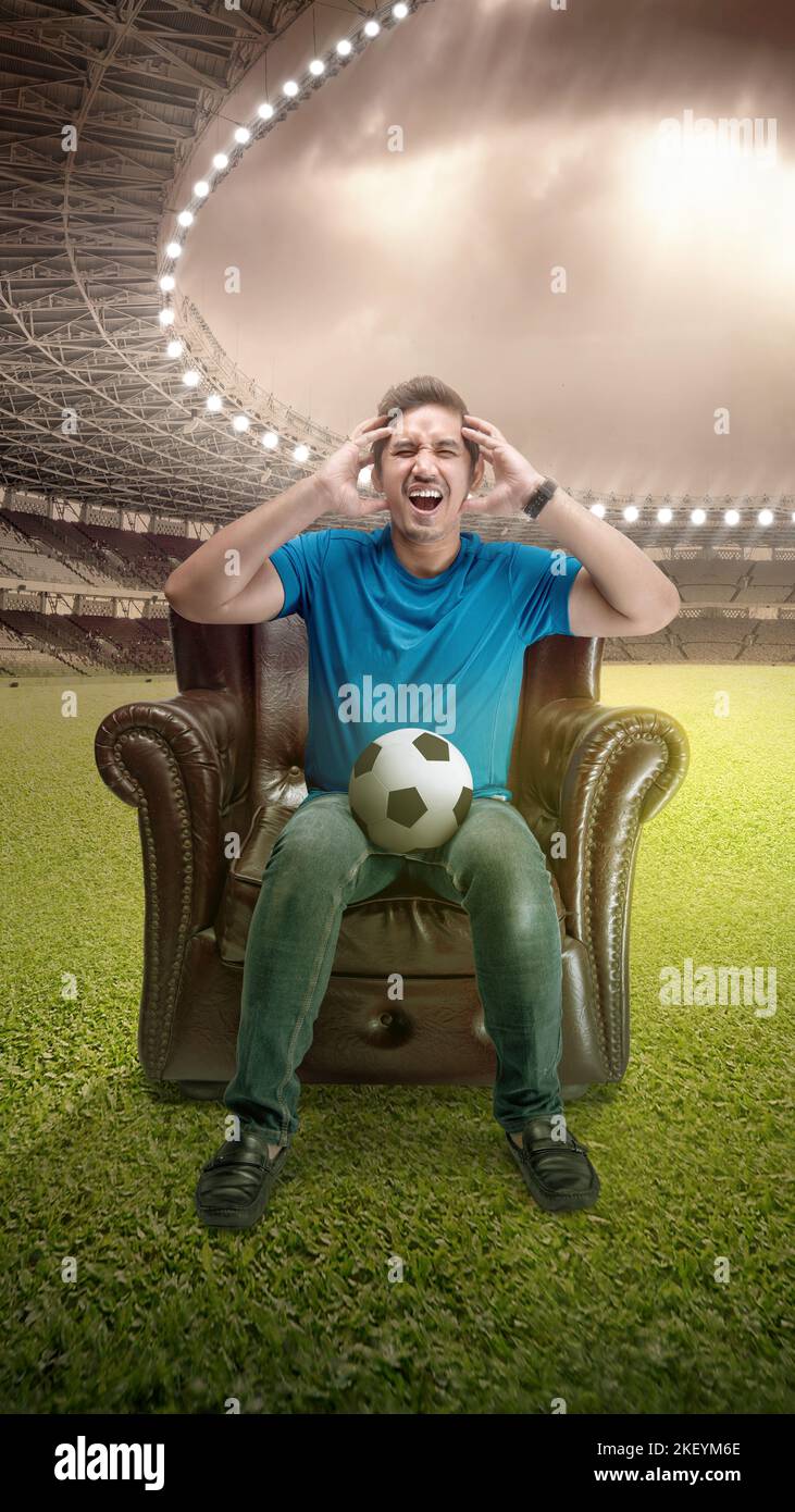 Asian man with the ball sitting on the couch with a disappointed ...