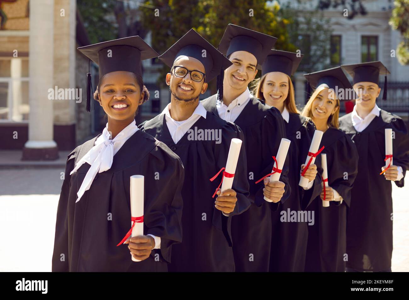 Outdoor group shot of happy diverse university graduates in caps and ...