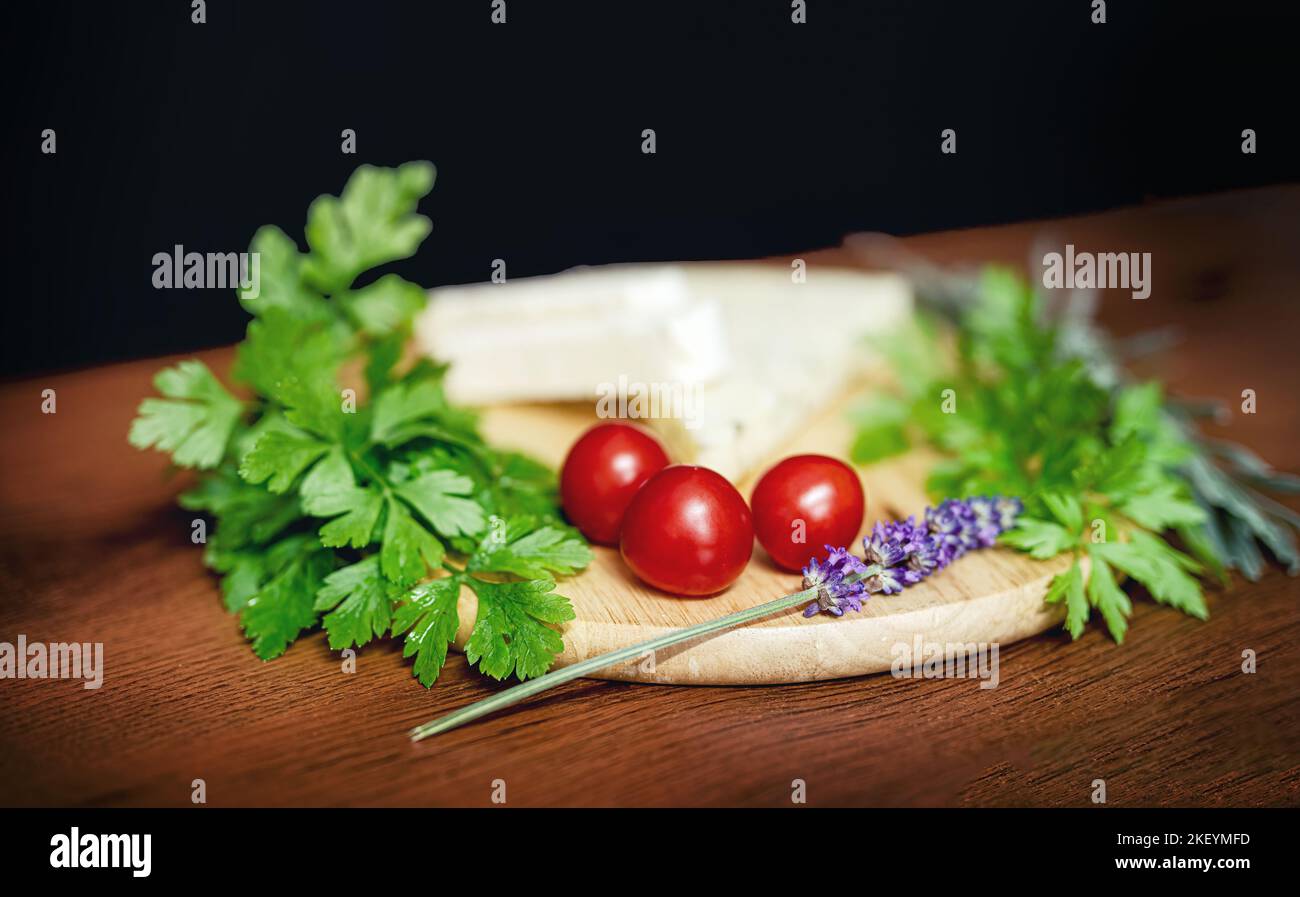 handmade rural cheese on a wooden board with vegetable decoration on ...