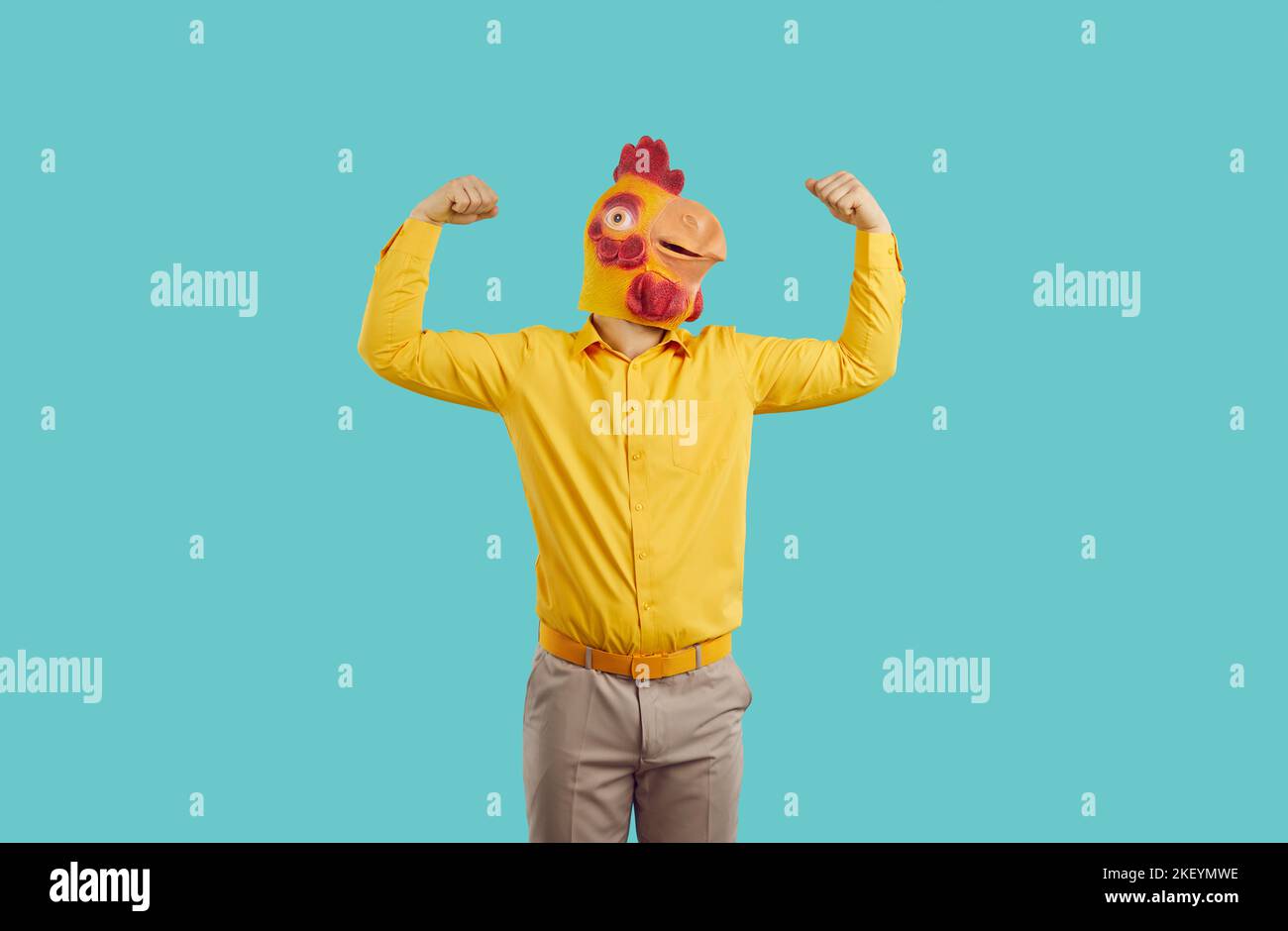 Weak young man in funny chicken mask pretending to be strong and ...