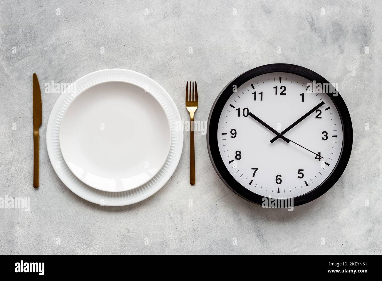 Round wall clock with empty plate. Diet or meal time concept Stock ...