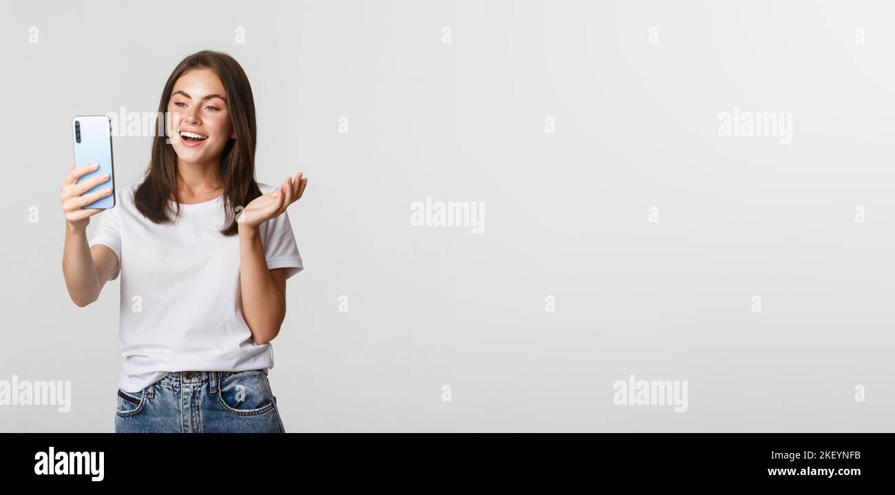 Friendly attractive girl video calling friend, smiling and having ...