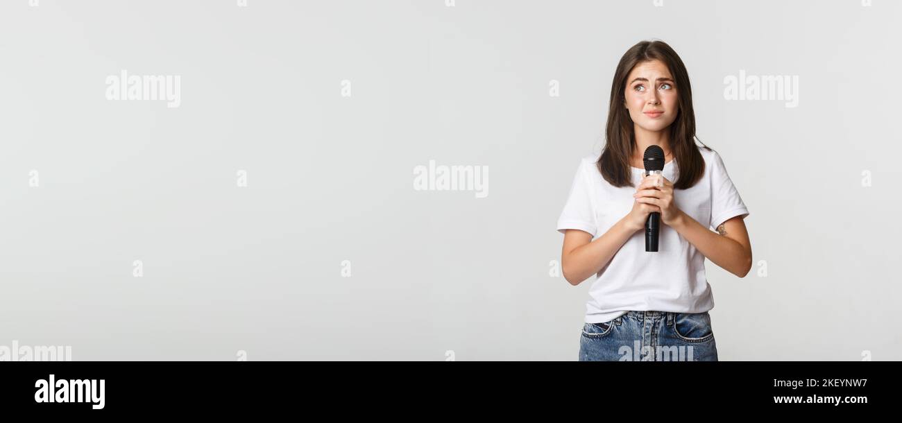Shy cute brunette girl scared of singing in public, standing with ...