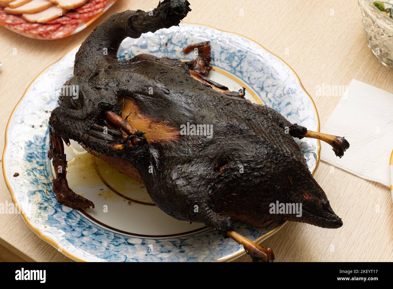 Burnt bird carcass on serving plate on dining table. Serve charred ...