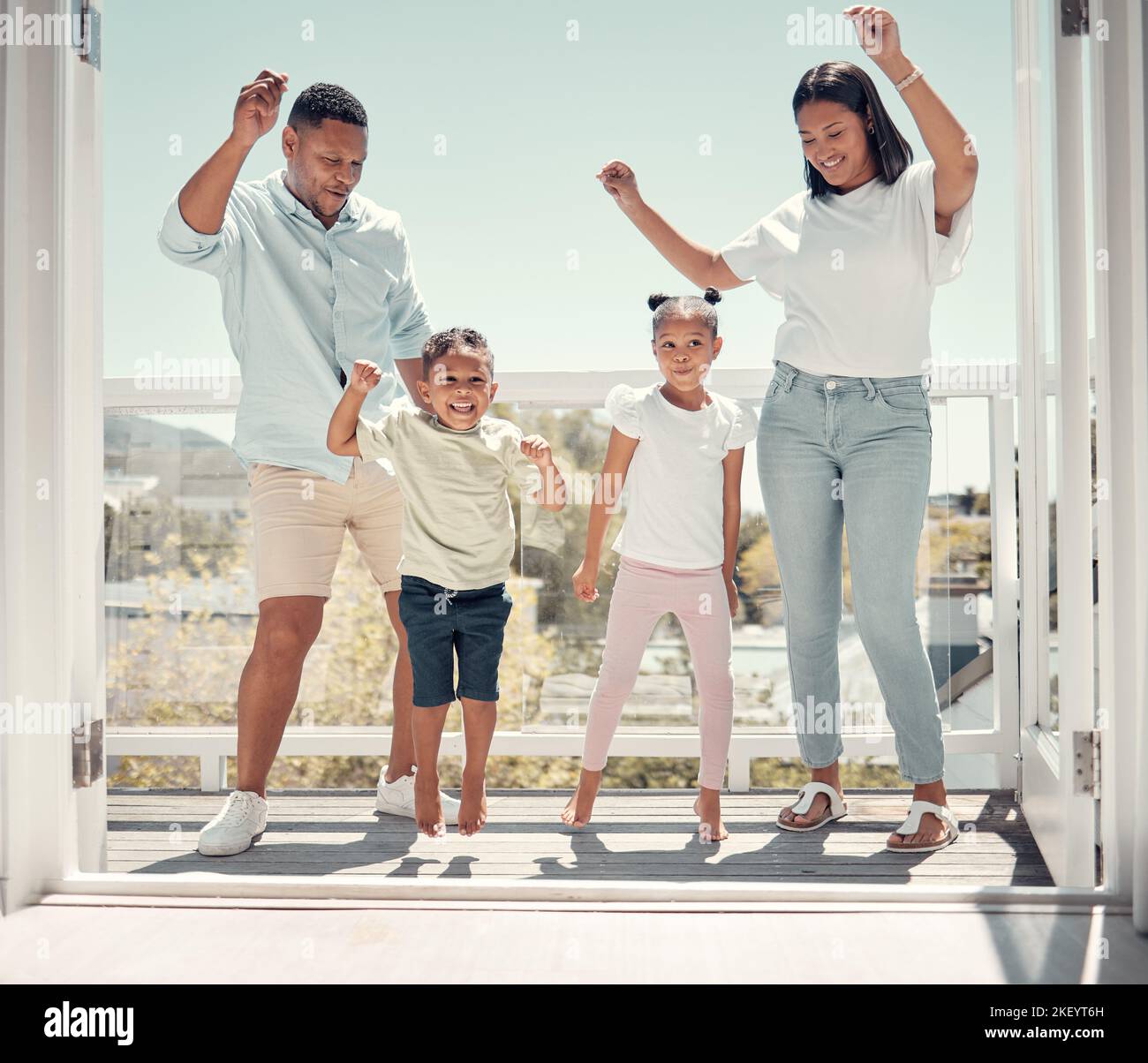 Happy family dancing, couple and kids on balcony of home having fun in ...
