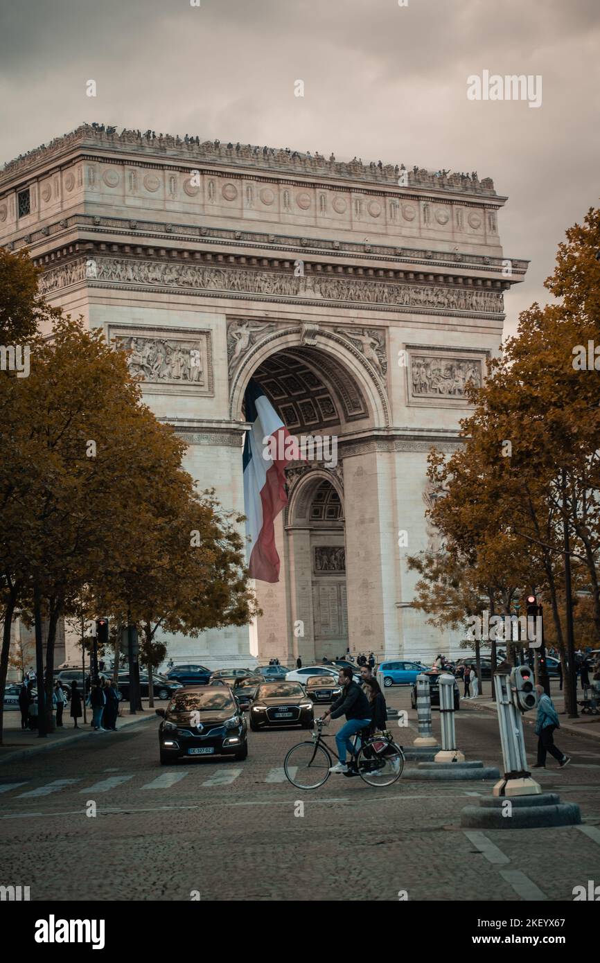 A vertical low-angle of the Triumphal Arc with autumn trees and cloudy ...