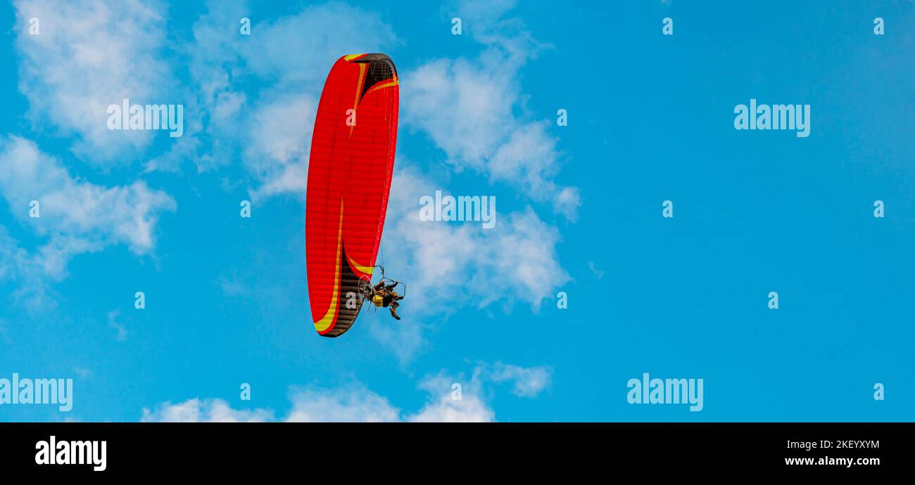 Against background of blue summer cloudy sky, tandem of paragliders ...