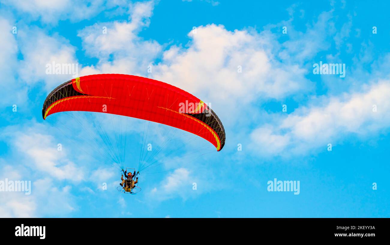 Against background of blue summer cloudy sky, tandem of paragliders ...