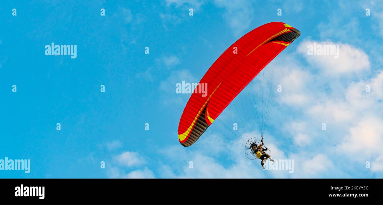 Against background of blue summer cloudy sky, tandem of paragliders ...