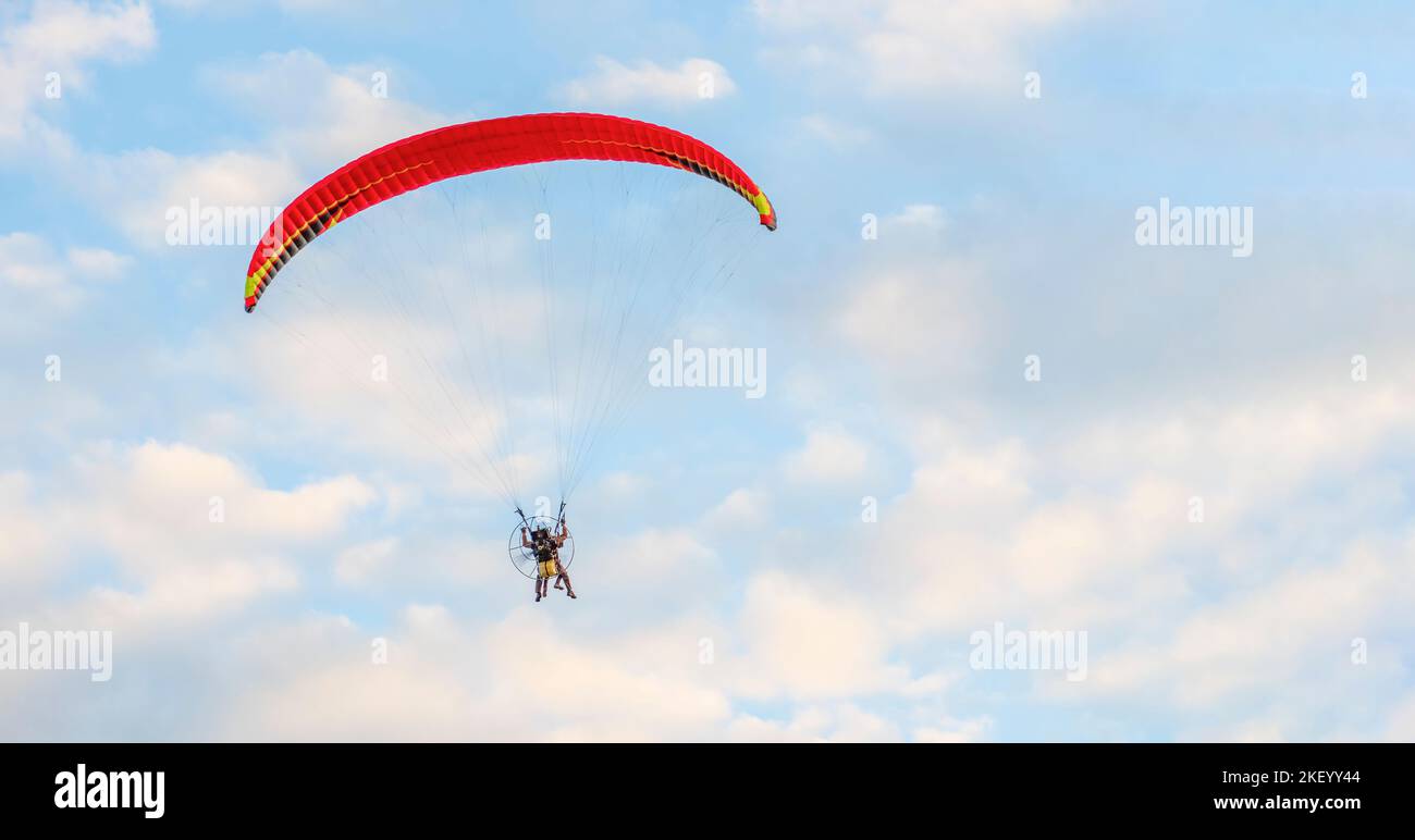 Against background of blue summer cloudy sky, tandem of paragliders ...