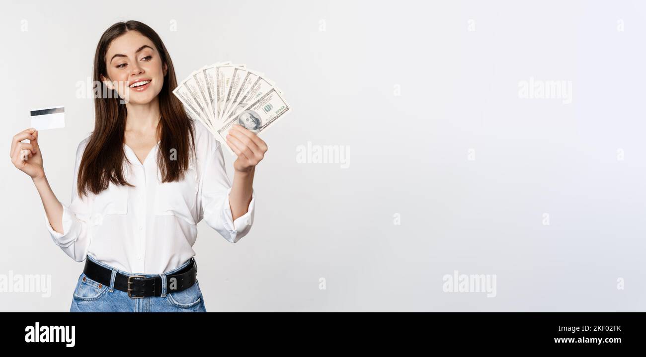 Happy modern woman holding money and credit card in hands, smiling ...
