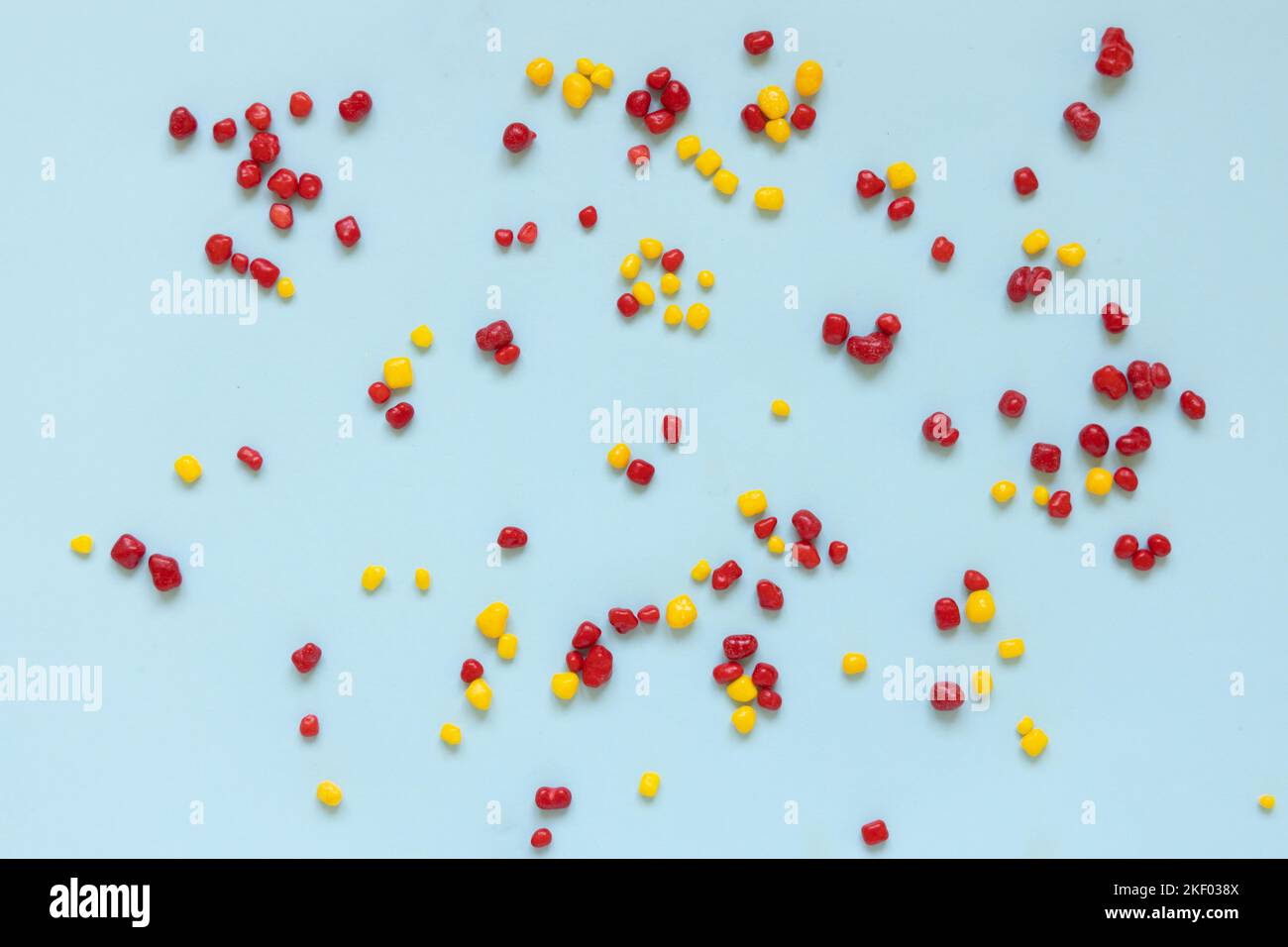Red and yellow colored candy nerds sprinkled on a blue background Stock ...