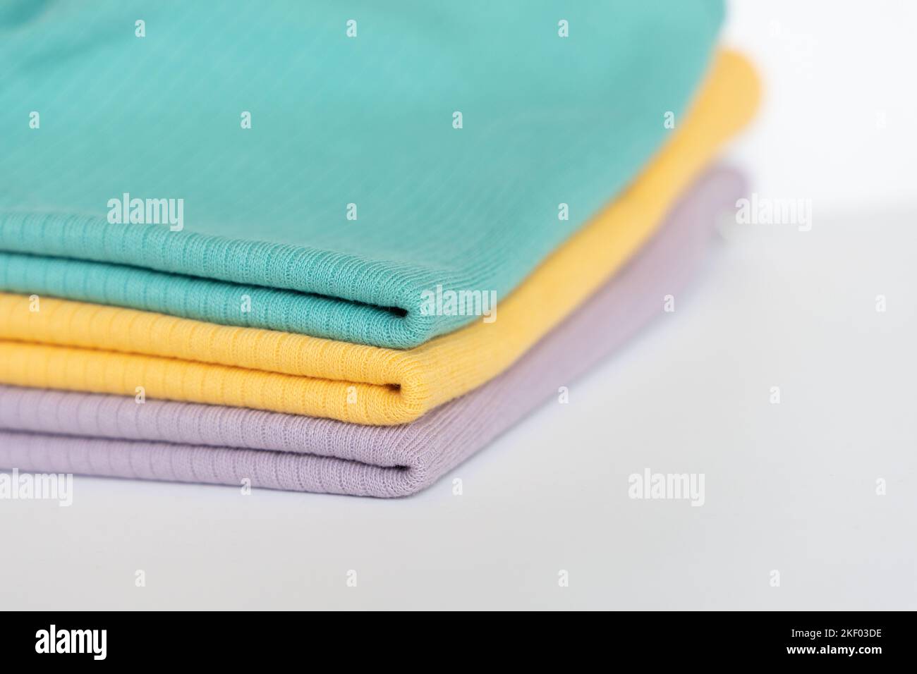 Stack folded purple, yellow, green baby cotton clothing on white ...