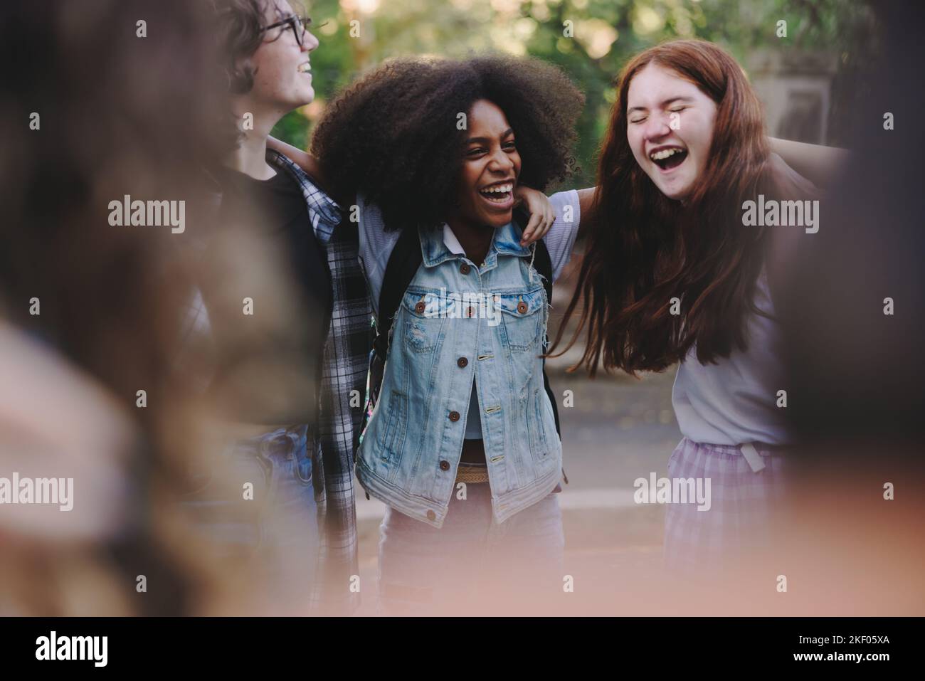 Happy teenage school kids embracing each other while standing in a ...