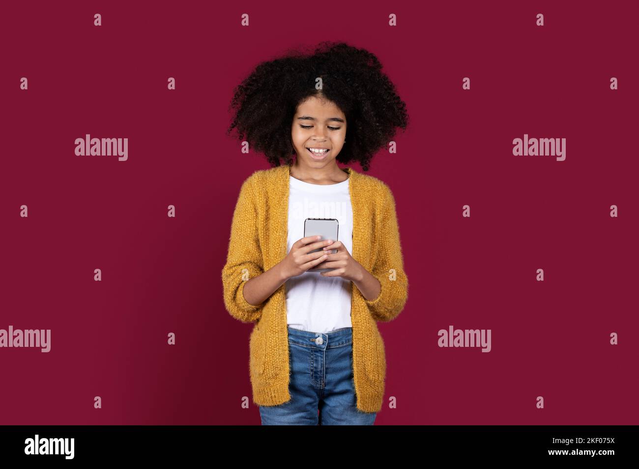 Smiling african american girl using cell phone, studio background Stock ...