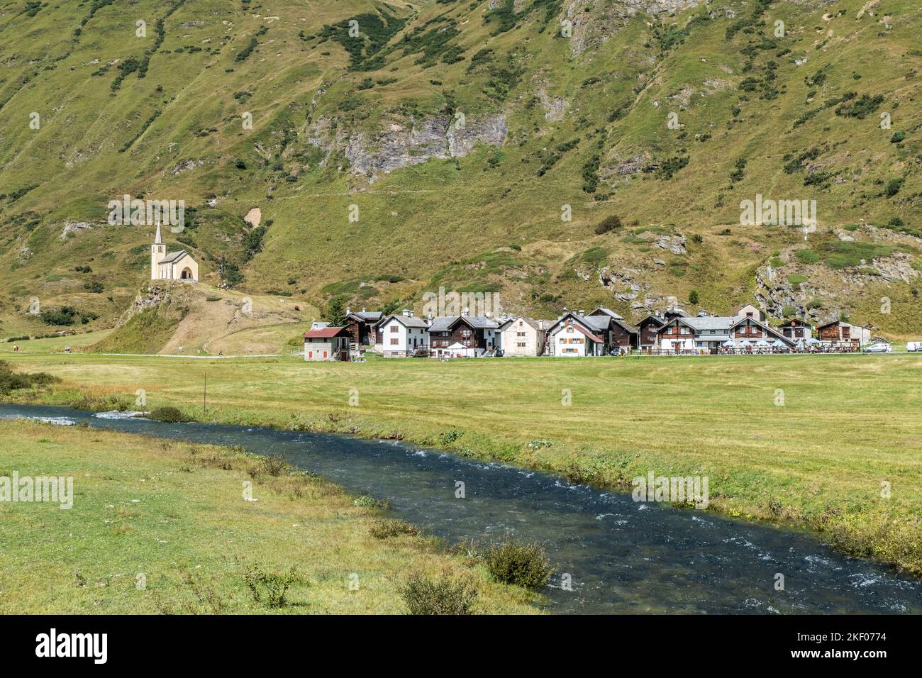 small village in the mountains with stone houses, flowers and a river ...