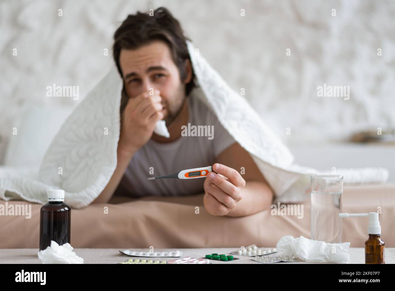 Unhappy Millennial European Man With Stubble Blows Nose In Napkin Lies