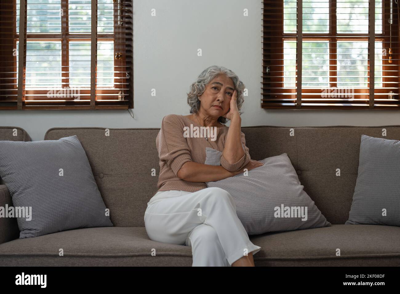 Portrait of worried senior woman sitting on sofa at home Stock Photo ...