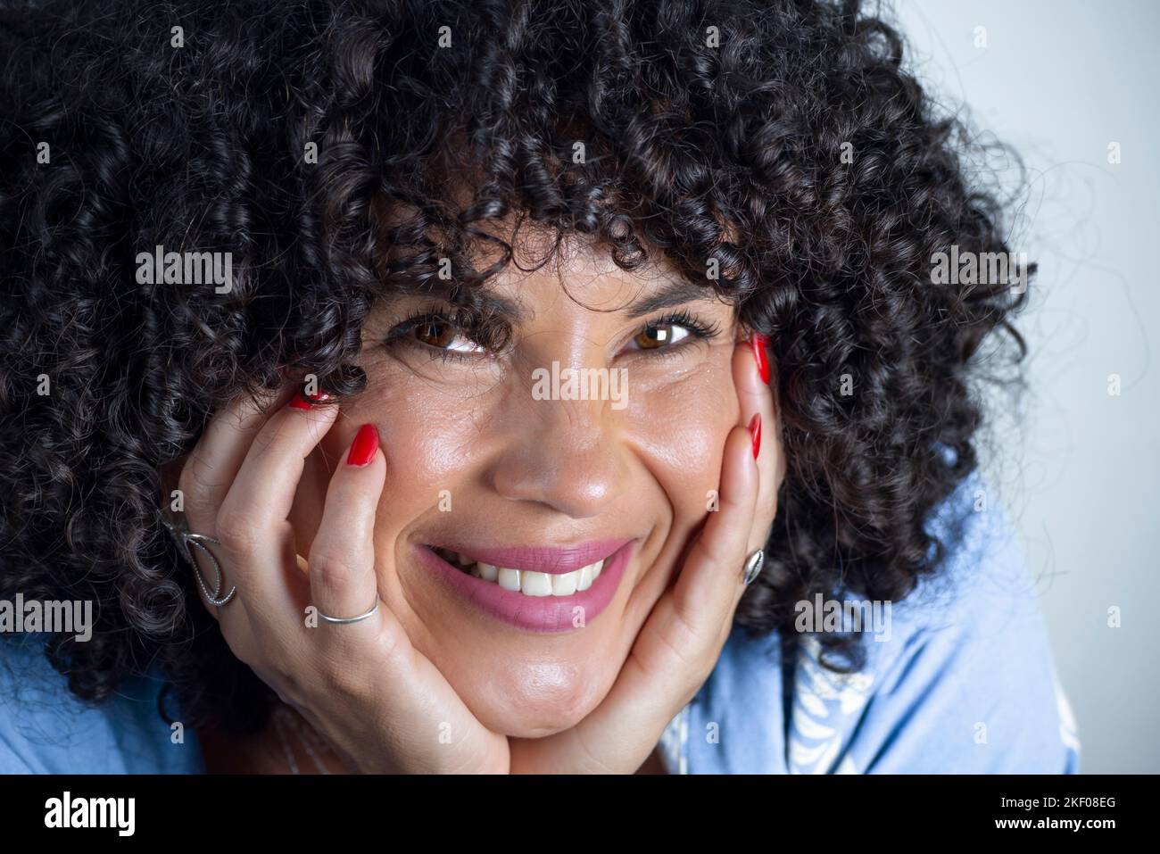 Portrait Of Smiling Beautiful Curly Hair Model Against Light Background