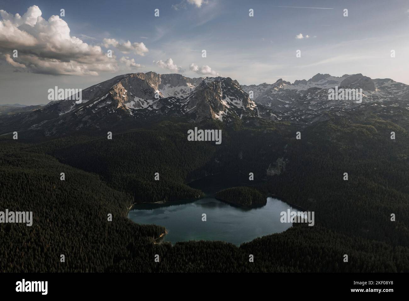 A beautiful lake surrounded by a dense forest and rocky mountains under ...