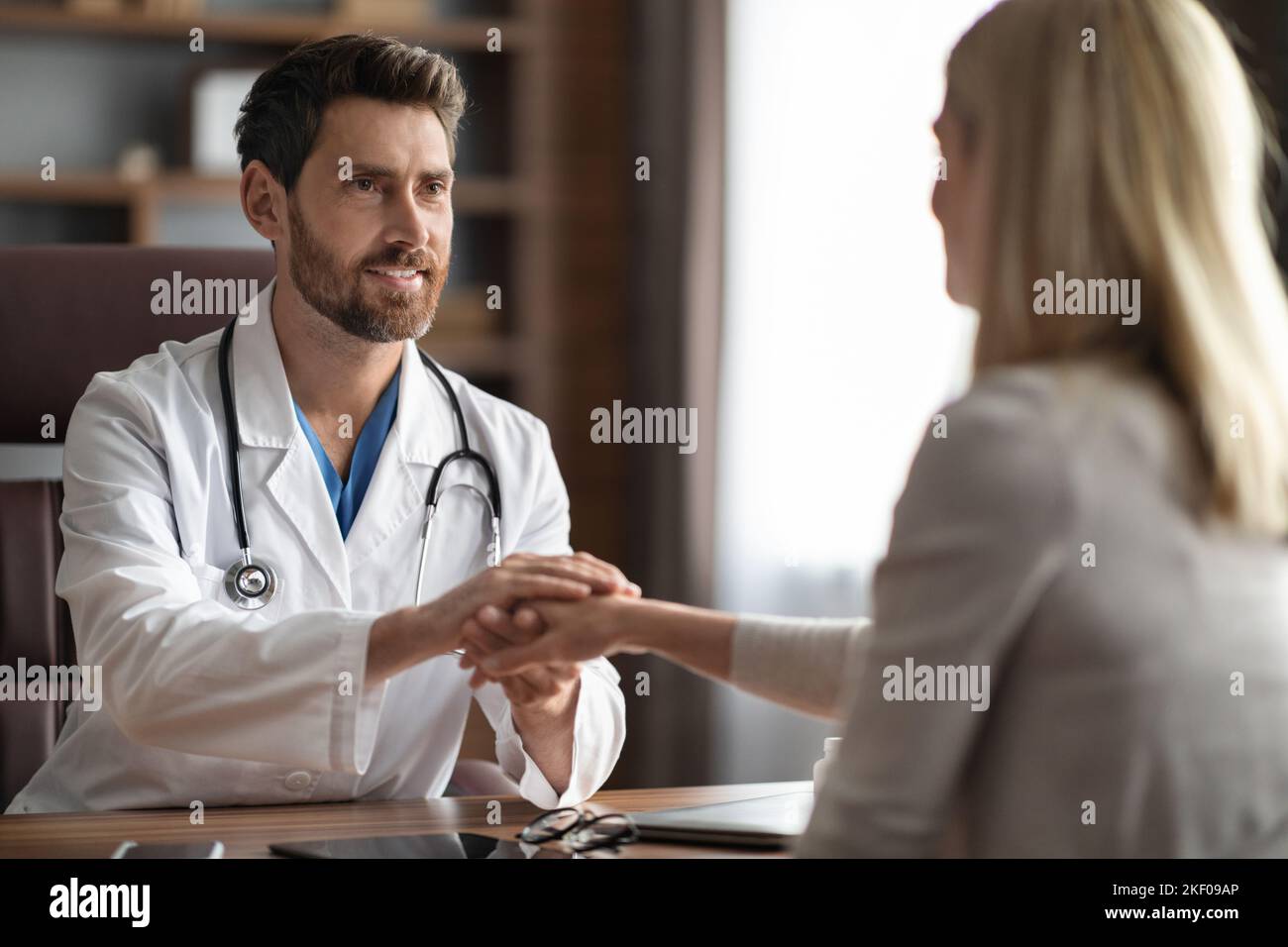 Smiling Male Doctor Holding Hand Of Female Patient During Meeting In ...