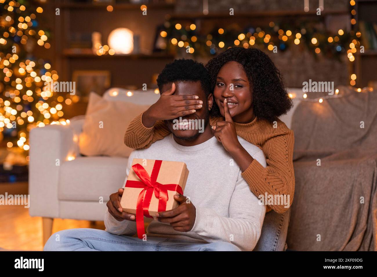 Smiling young african american wife closes eyes to husband, shows ...