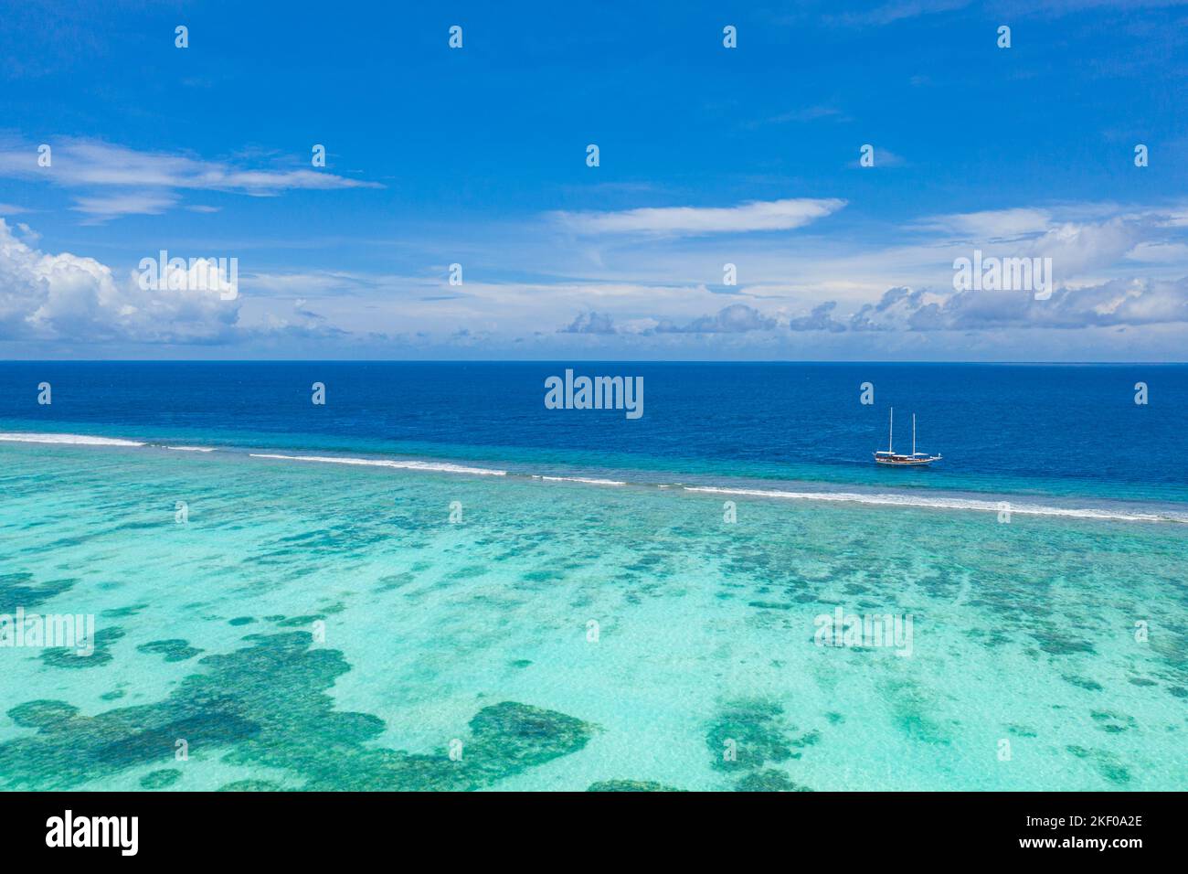Small yacht sailing in tropical sea over coral reef in Indian ocean ...