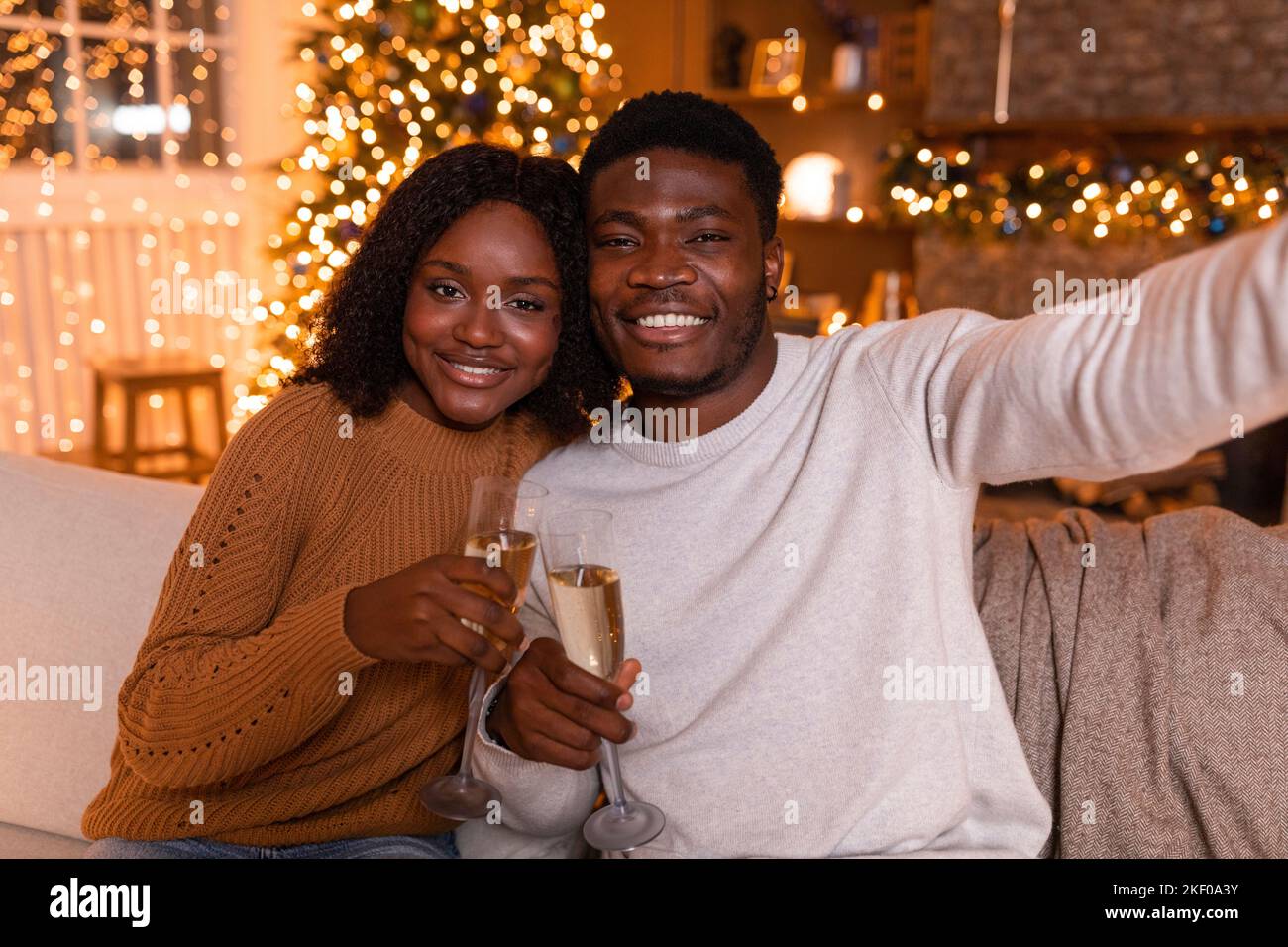 Happy young african american couple cheers with champagne glasses, make ...