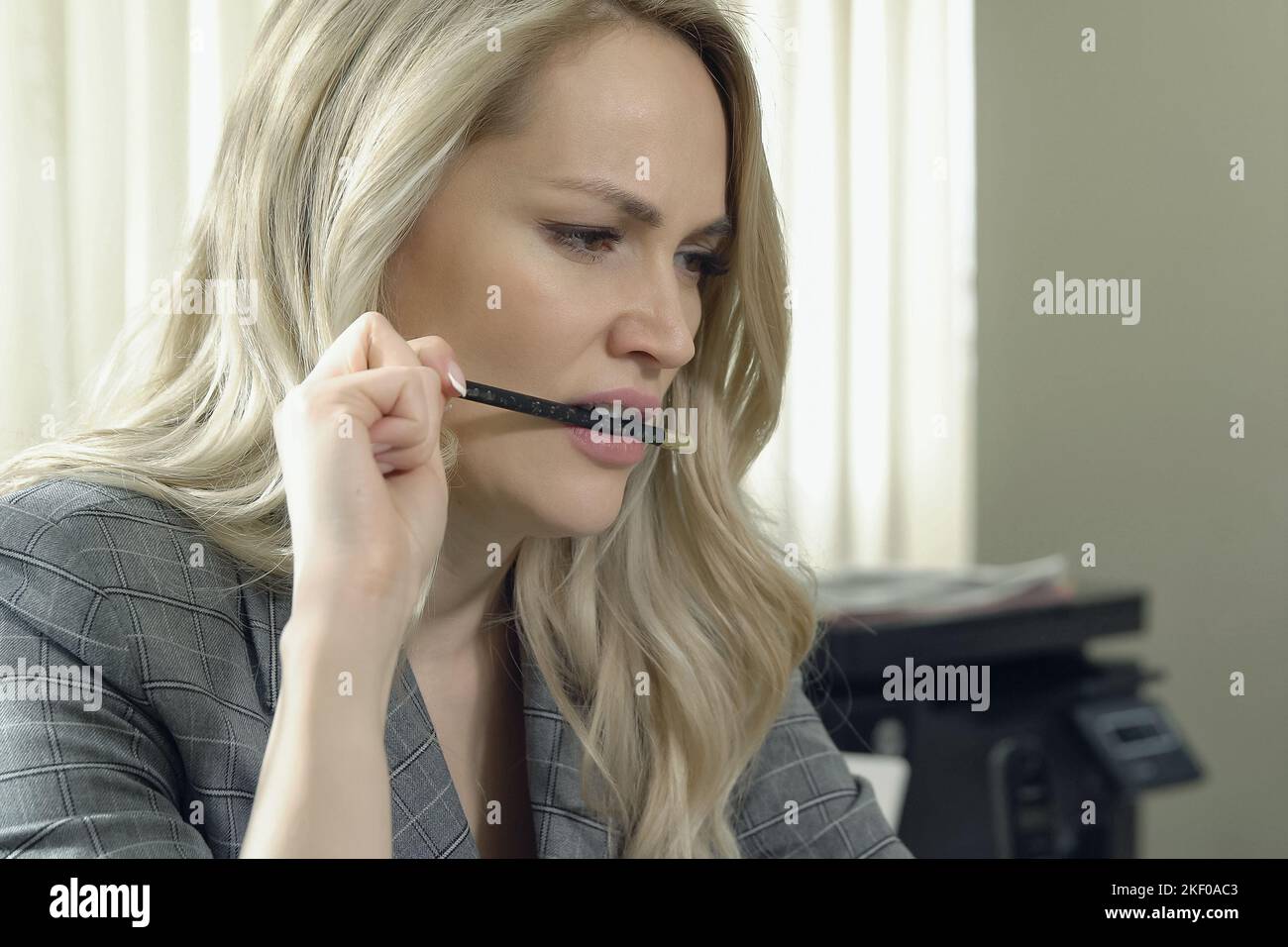 beautiful business woman biting her pencil in office Stock Photo - Alamy