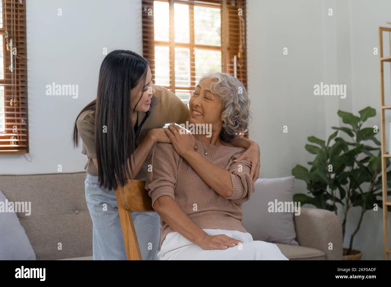 Loving adult daughter hugging older mother on couch at home, family ...