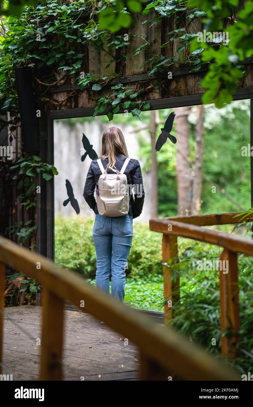 A vertical shot of a woman with a backpack standing in the park against ...
