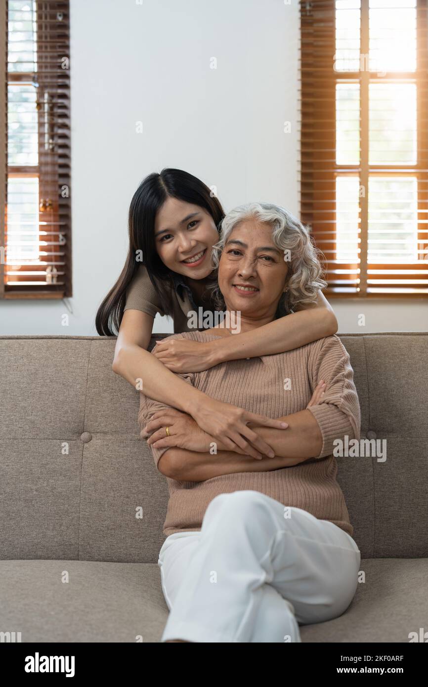 Loving adult daughter hugging older mother on couch at home, family ...
