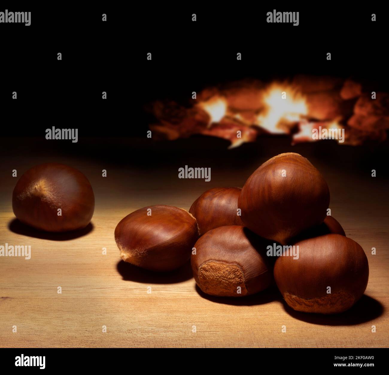 Chestnuts on a wood table with campfire roaring behind Stock Photo - Alamy