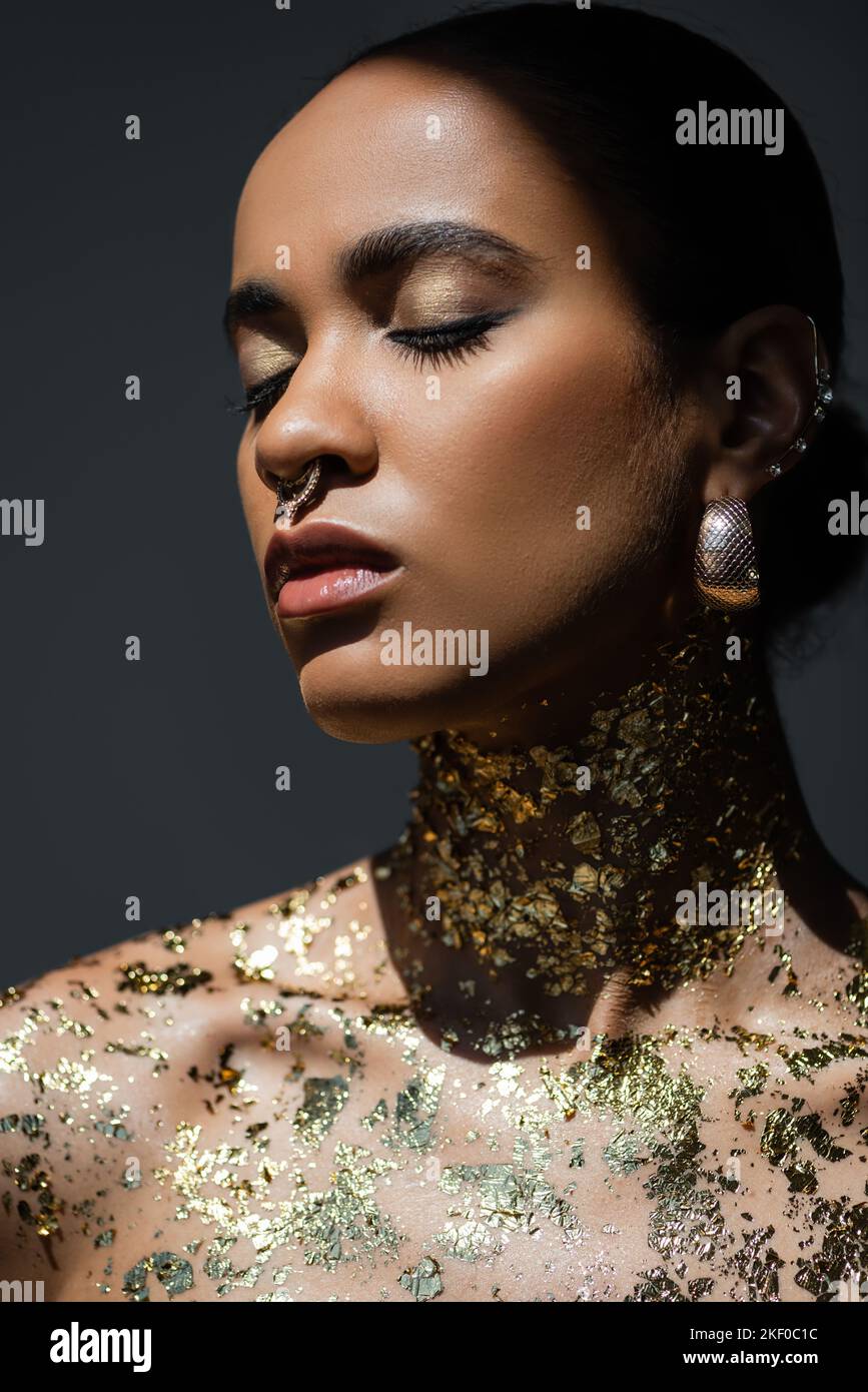 Portrait of young african american woman with golden foil on body ...